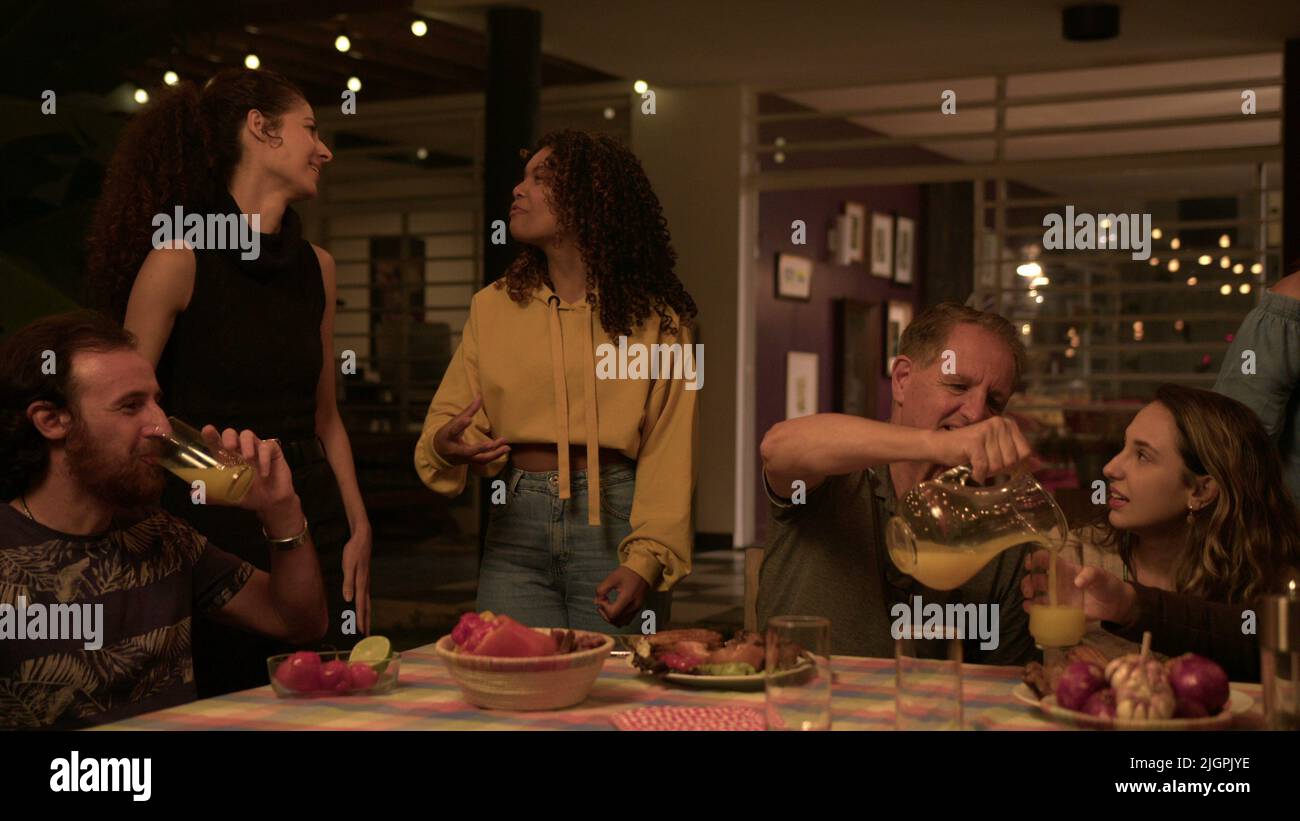 Family and friends at night together around table in backyard in ...