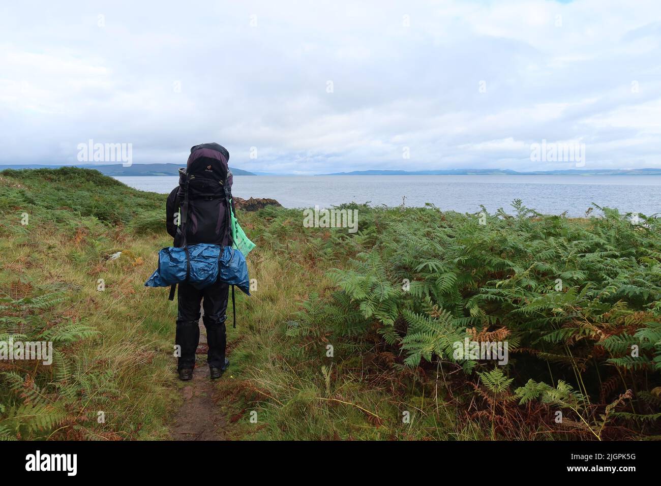 Solo Backpacker hiking with a big backpack. Arran Coastal Way. Isle of ...