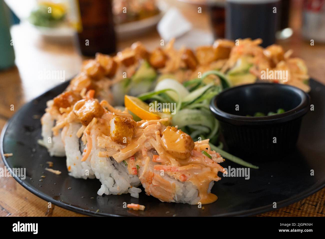 Sushi roll plate with breaded prawn and sauce on top. Traditional ...