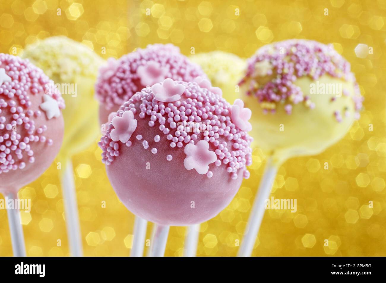 Pink and yellow cake pops decorated with sprinkles. Party dessert Stock ...