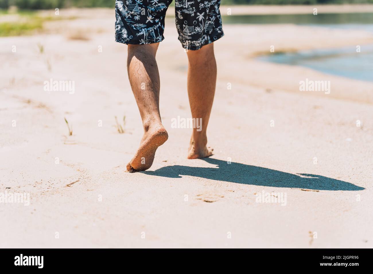 Man in shorts walking on the sandy beach Stock Photo - Alamy