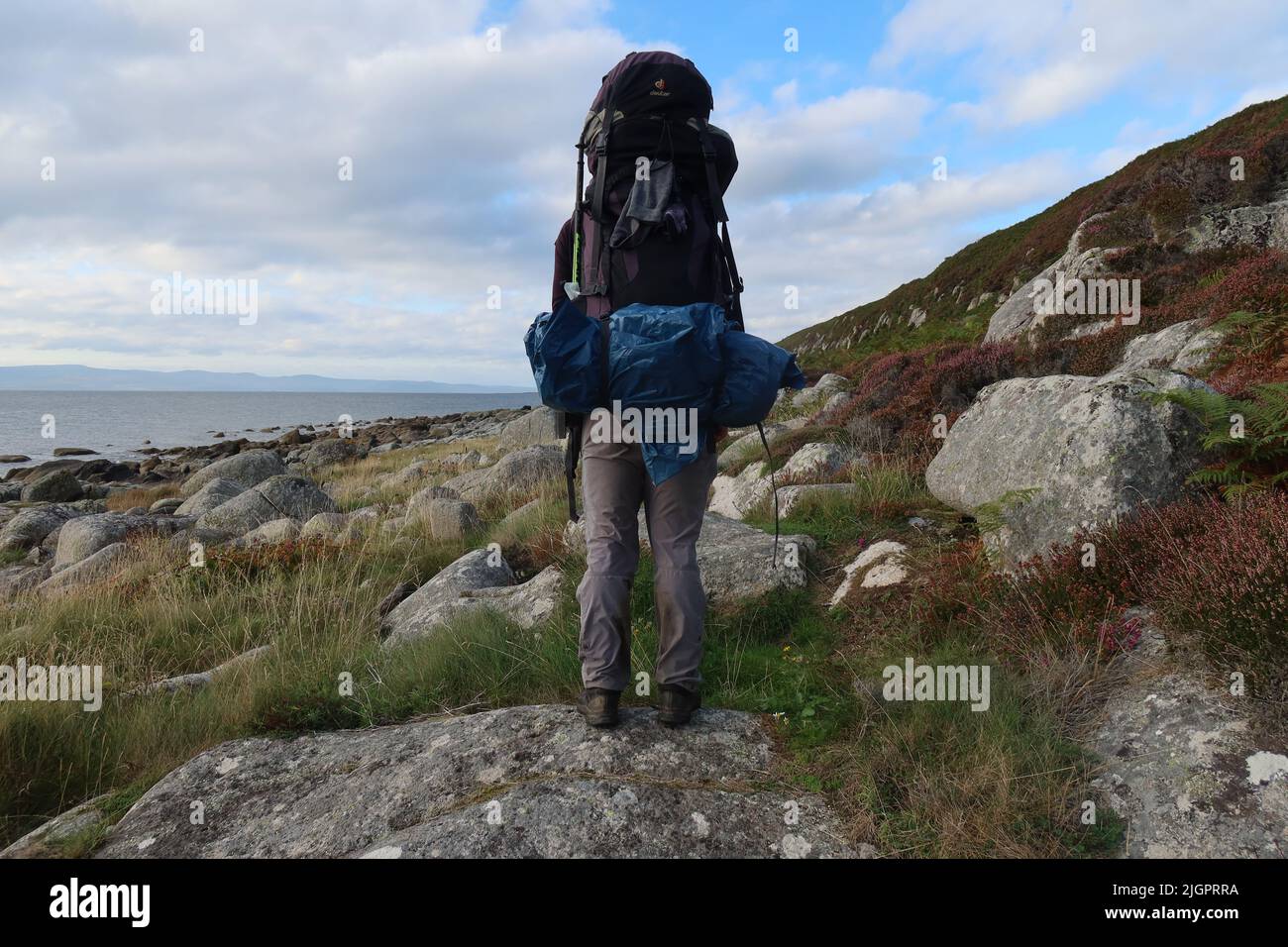 Solo Backpacker hiking with a big backpack. Arran Coastal Way. Isle of ...