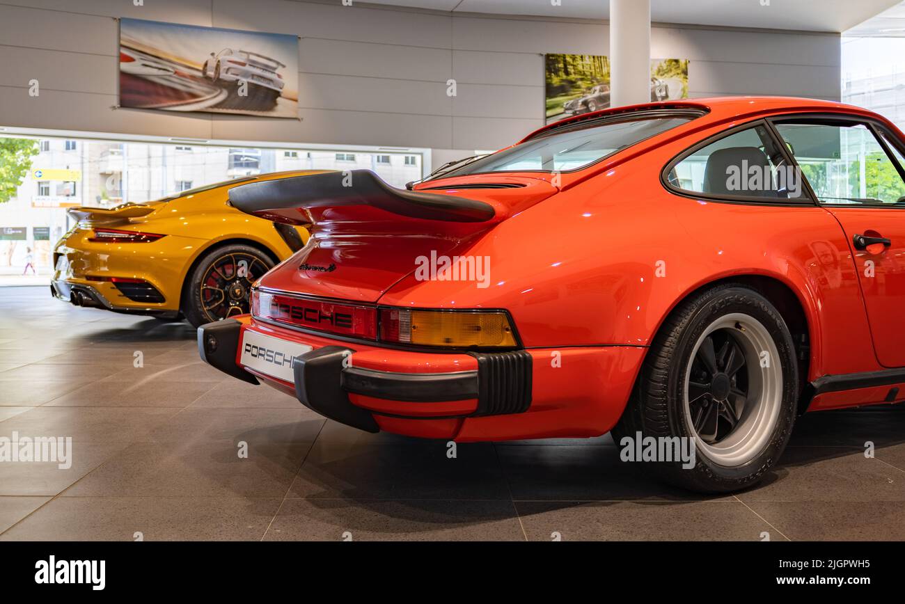 A picture of a red Porsche 911 Carrera 3.0 next to an orange Porsche ...