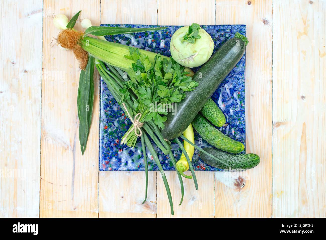 Multiple green vegetables on a blue glass plate. Healthy eating concept ...