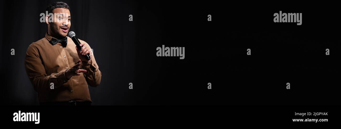 indian comedian in shirt and bow tie holding microphone during ...