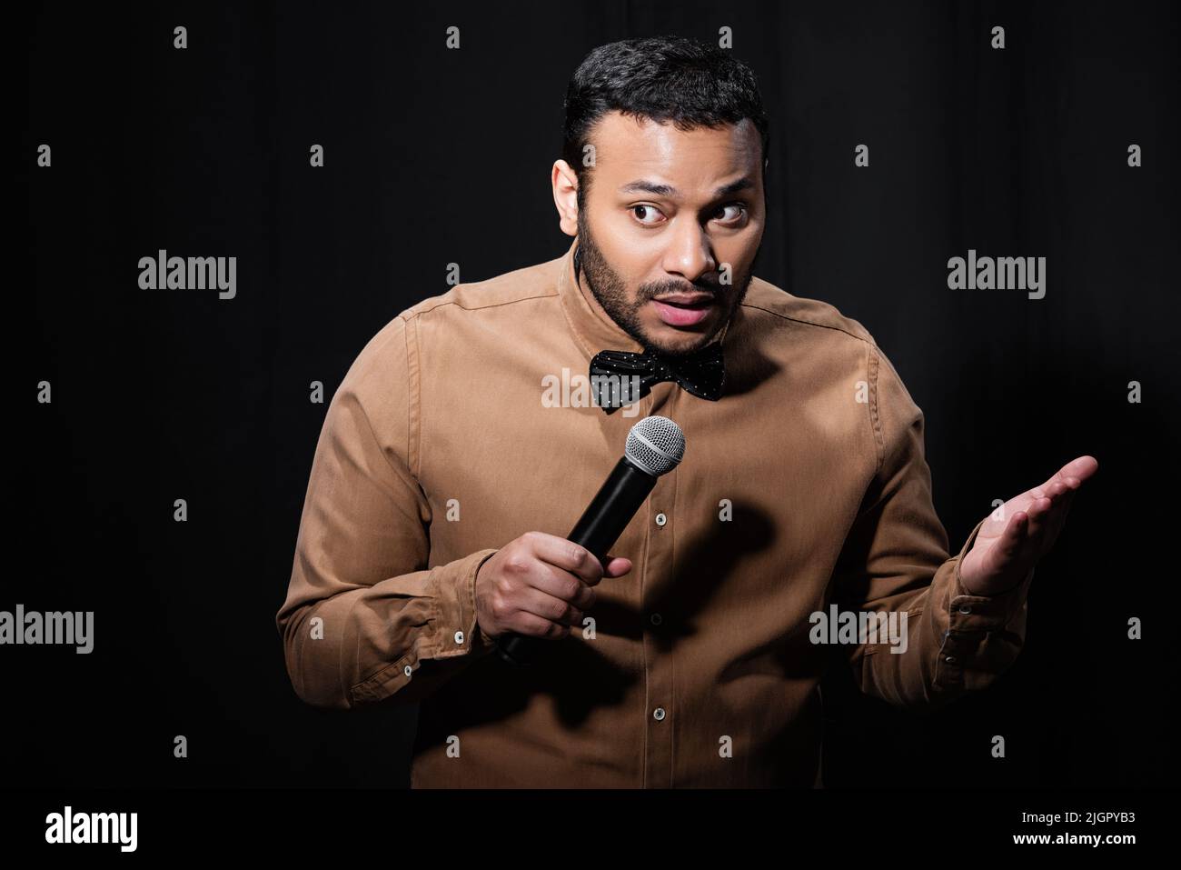 indian stand up comedian gesturing while telling jokes into microphone ...