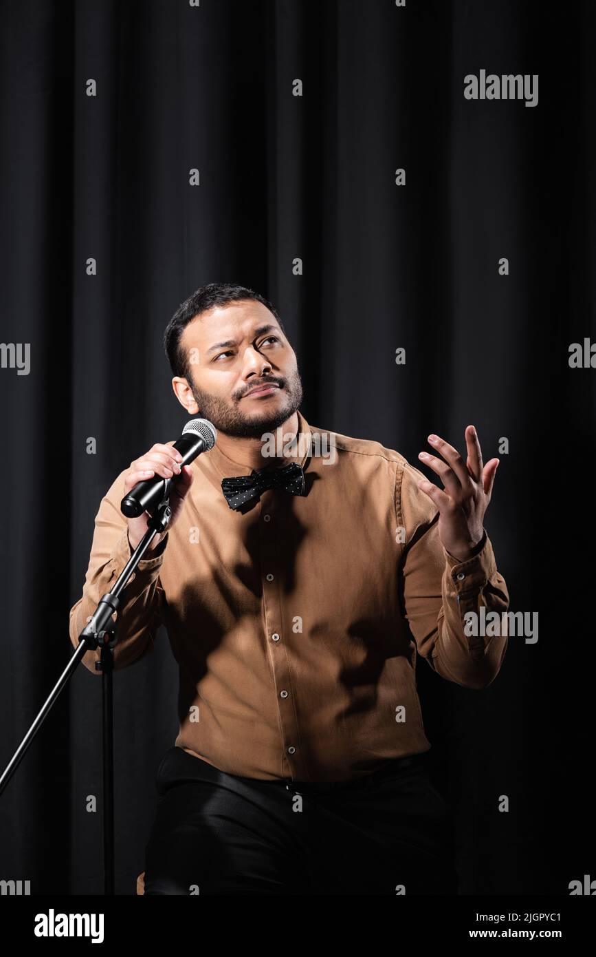 pensive indian comedian performing stand up comedy and telling jokes in ...