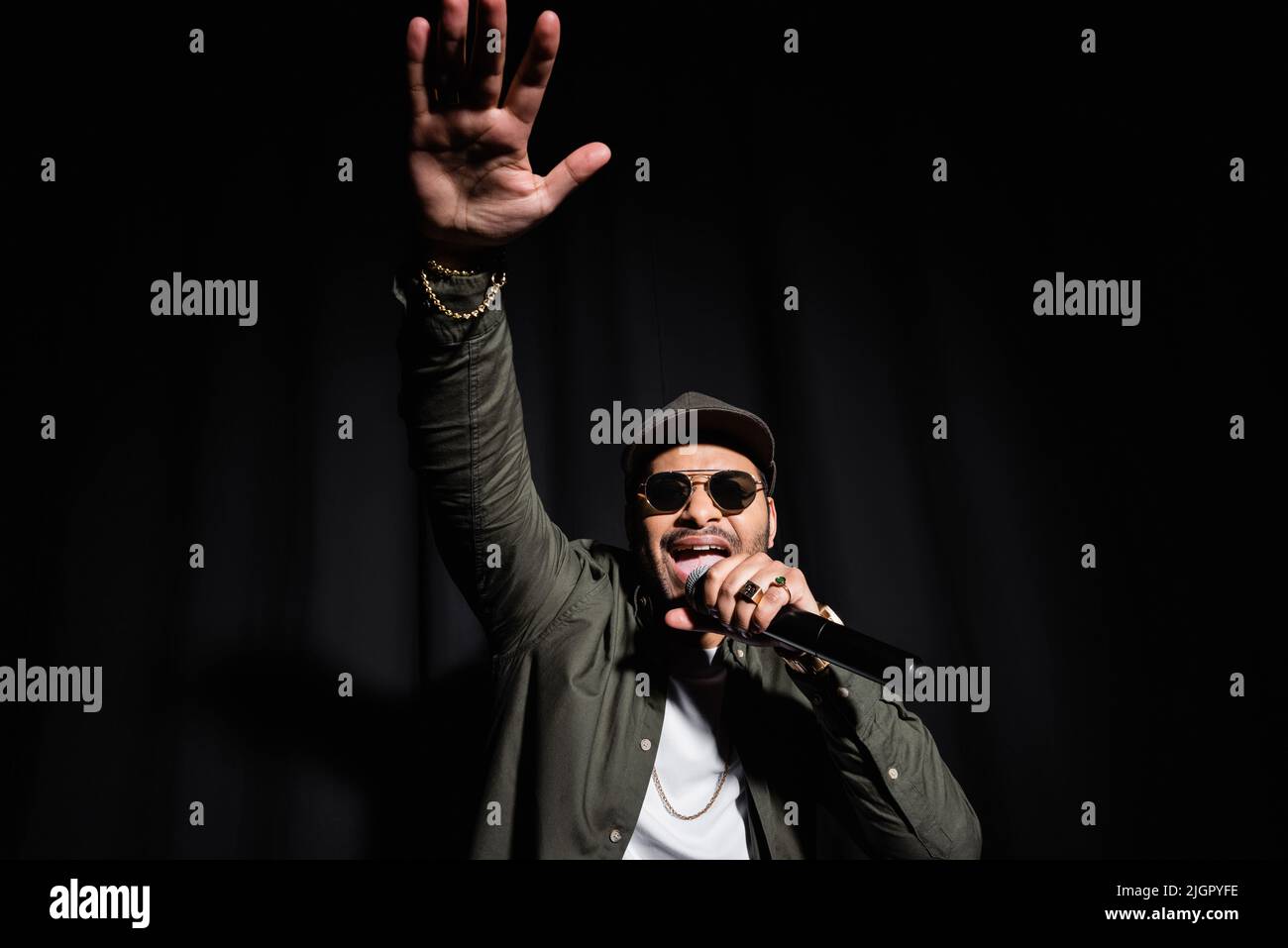 emotional middle east hip hop performer with raised hand singing in ...