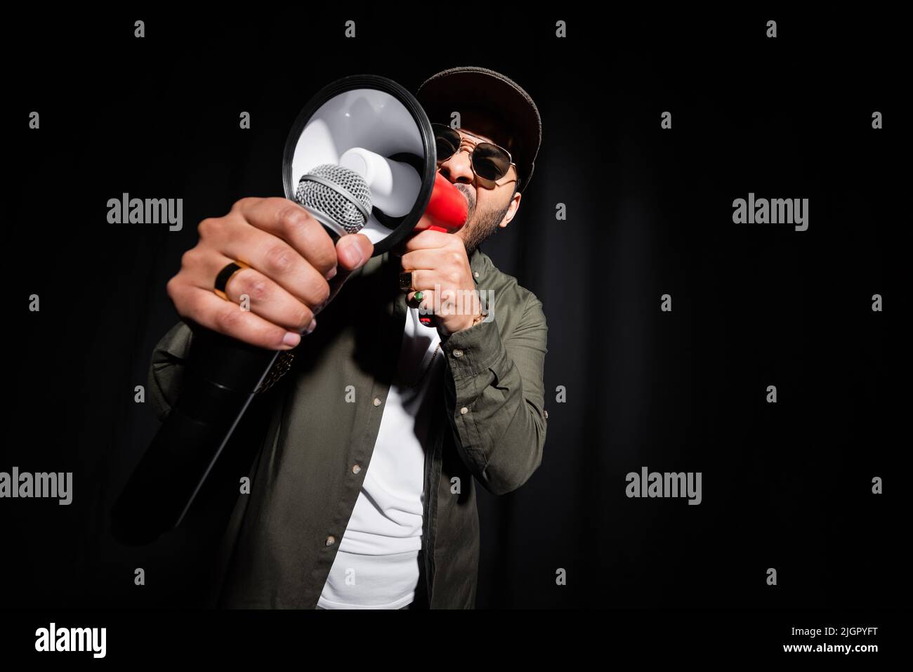 middle east hip hop singer in sunglasses and cap singing in microphone ...