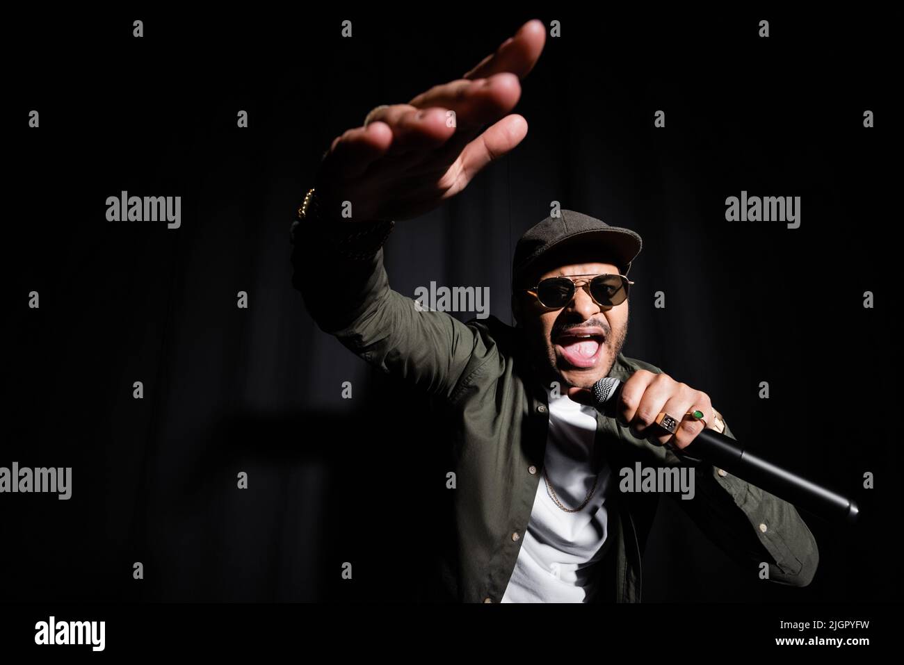 emotional indian hip hop performer with raised hand singing in ...