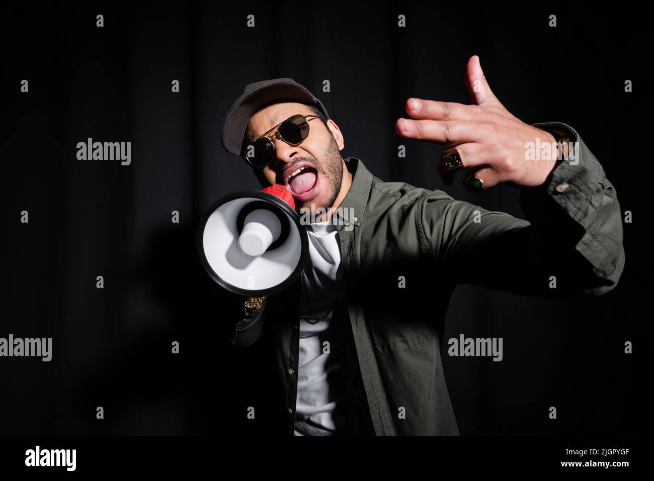 emotional middle east hip hop performer in sunglasses and cap singing ...