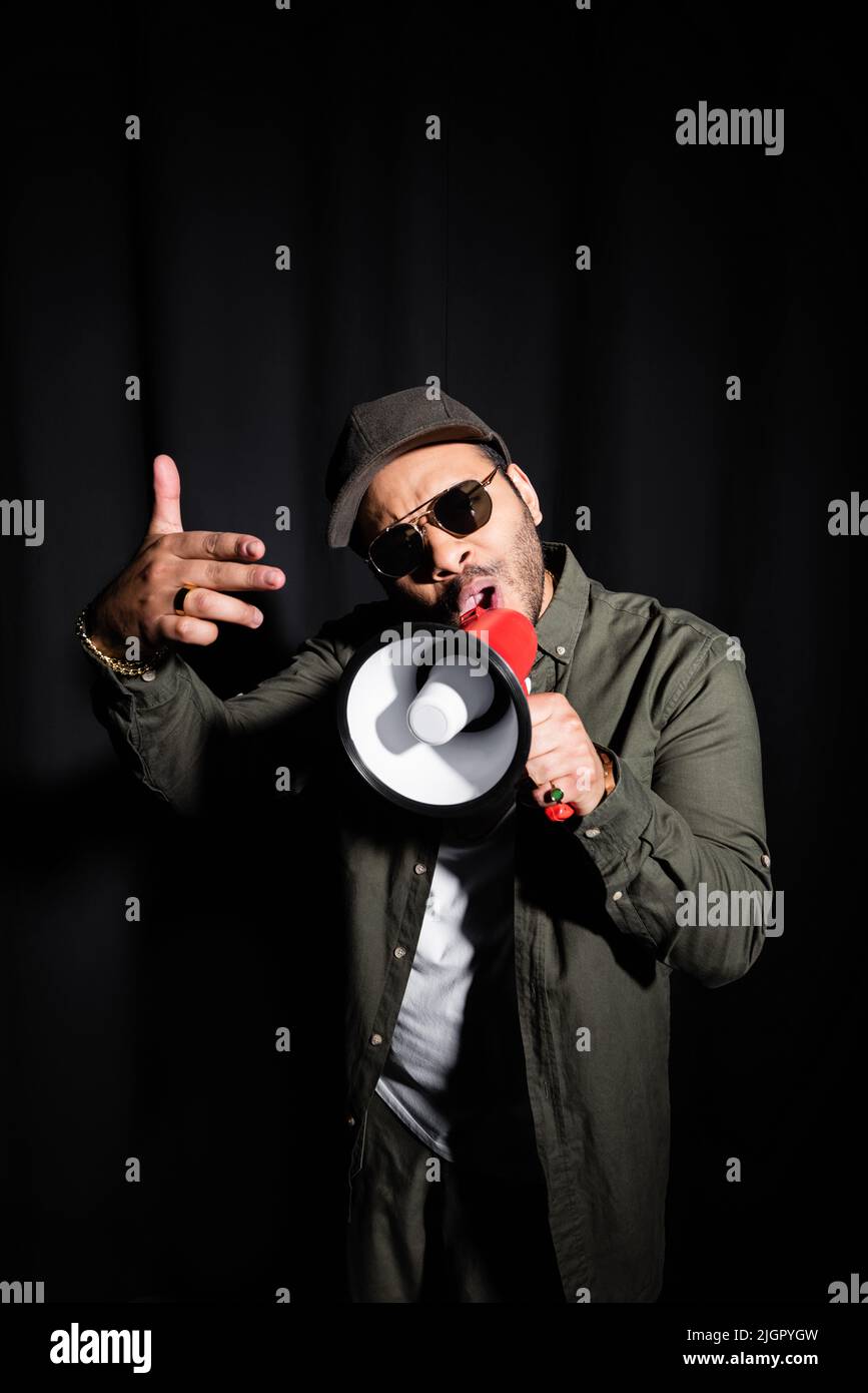 emotional middle east hip hop performer in sunglasses and cap talking ...