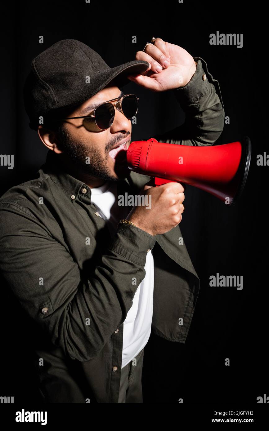 indian hip hop singer in sunglasses and cap screaming in megaphone on ...