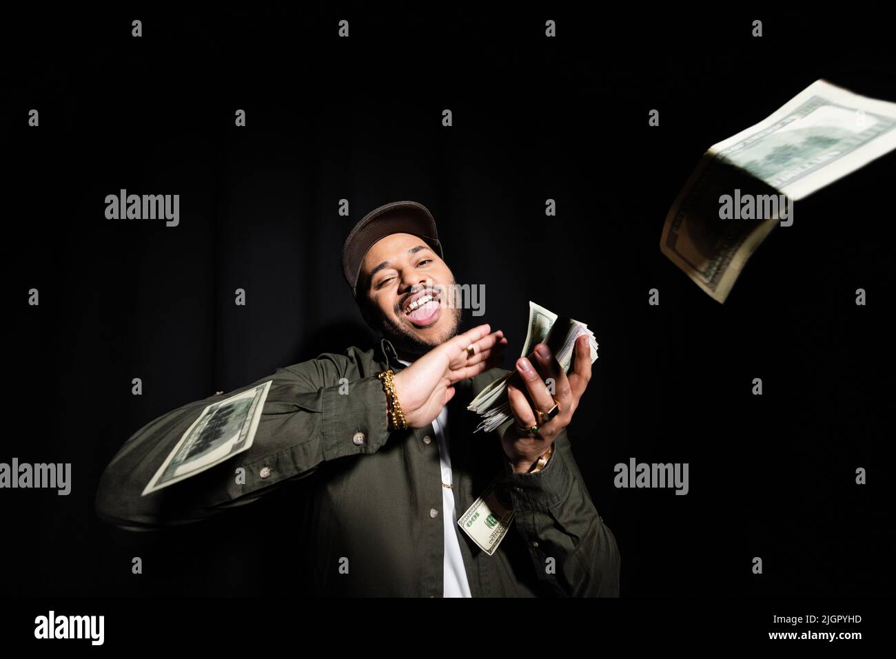 excited and rich indian hip hop performer in cap throwing dollar ...