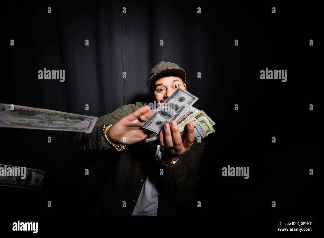 rich indian hip hop performer throwing dollar banknotes on black Stock ...