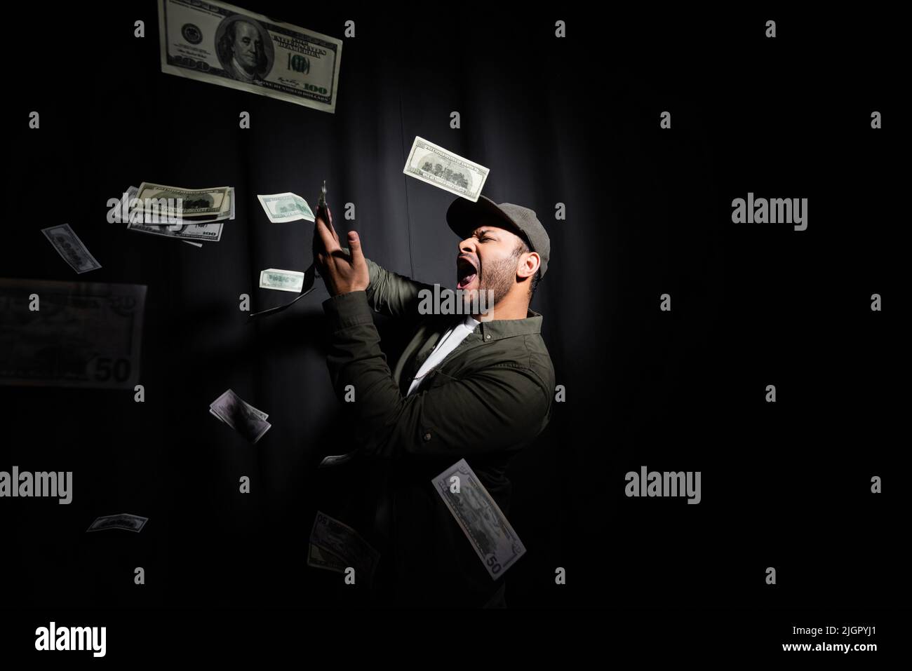 excited eastern hip hop performer in cap throwing dollar banknotes on ...