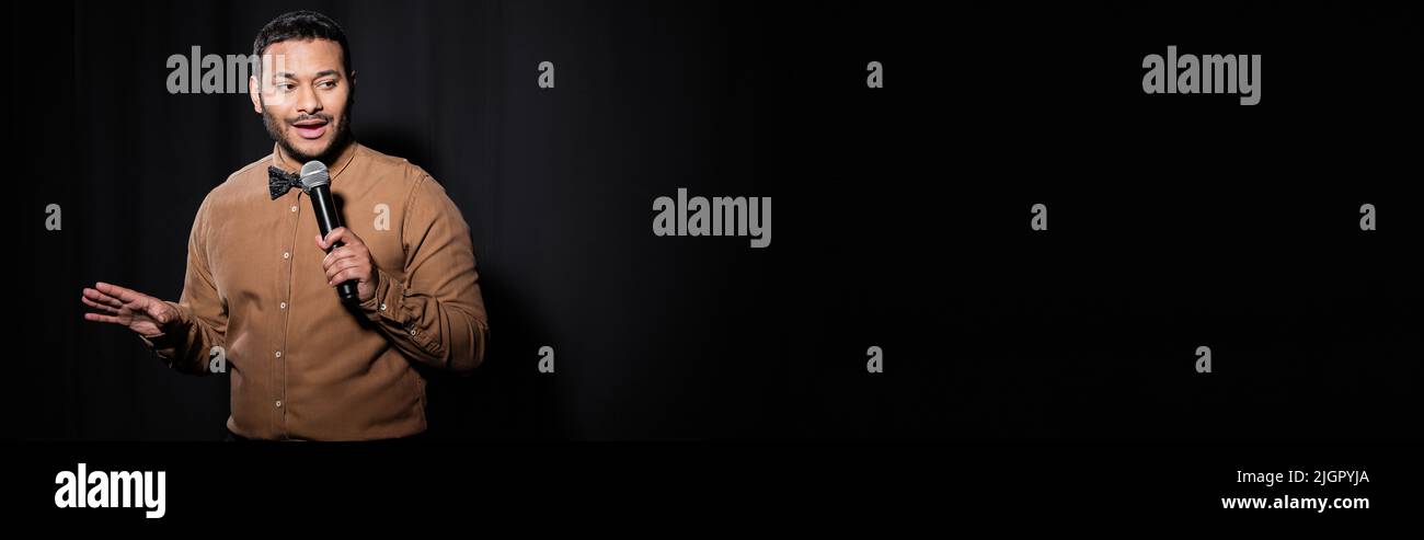 indian stand up comedian with bow tie holding microphone during ...