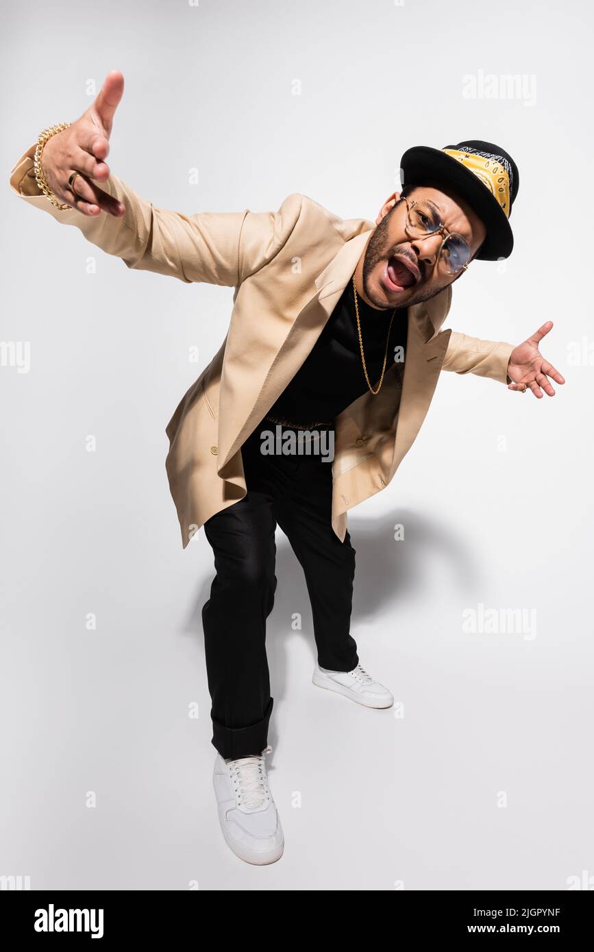 full length of eastern hip hop performer in fedora hat and eyeglasses ...