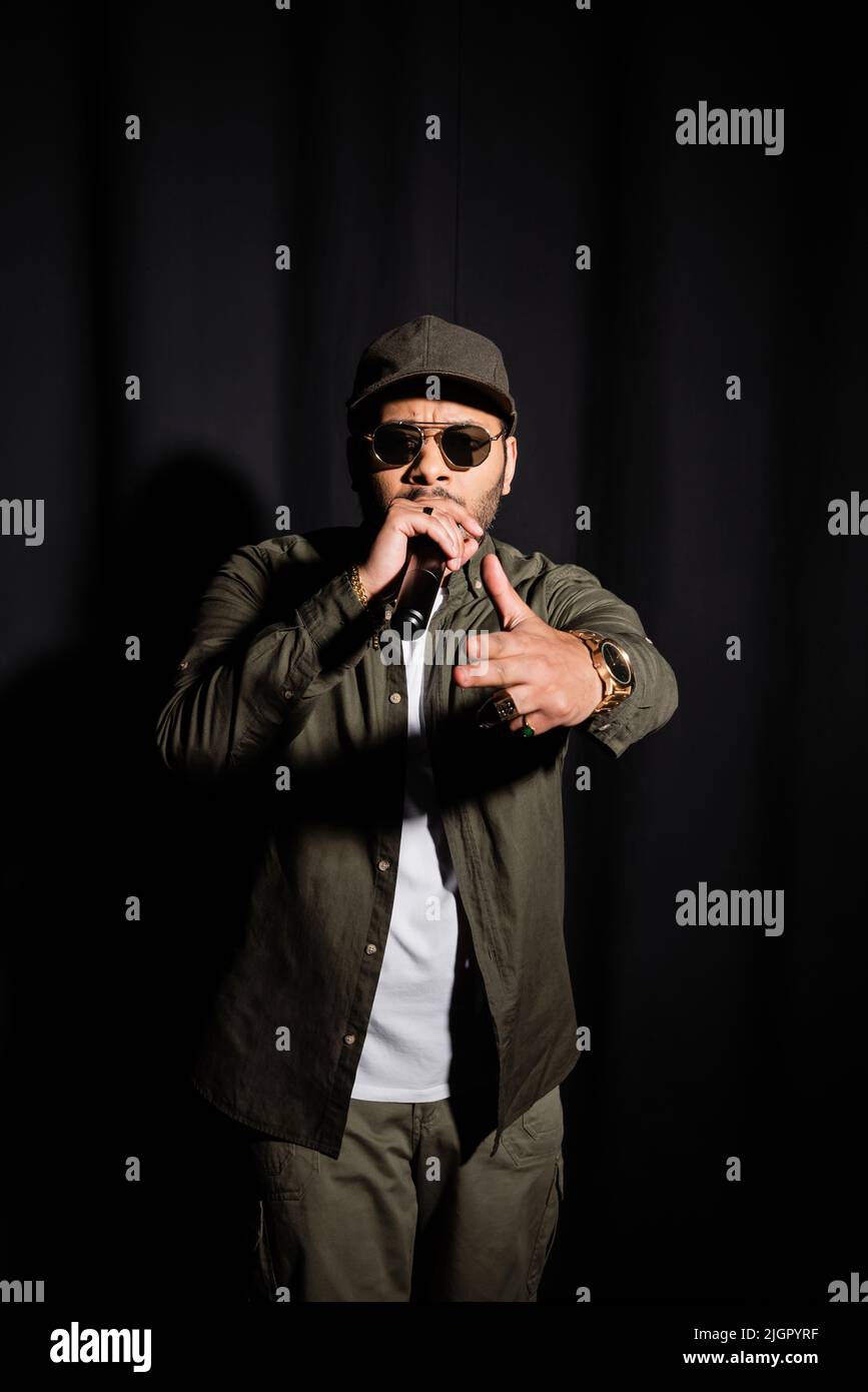 eastern hip hop performer in sunglasses singing in microphone and ...