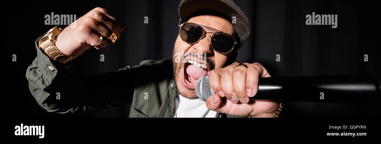 indian hip hop performer in sunglasses and cap singing loud in ...