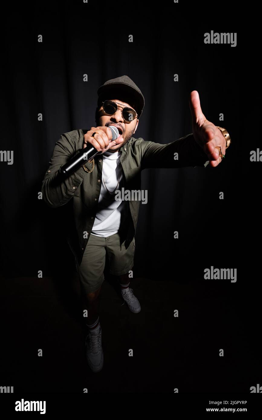 emotional middle east hip hop performer in sunglasses and cap singing ...