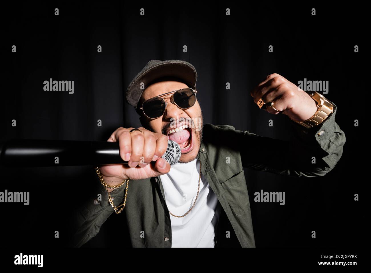indian hip hop performer in sunglasses and cap singing loud in ...
