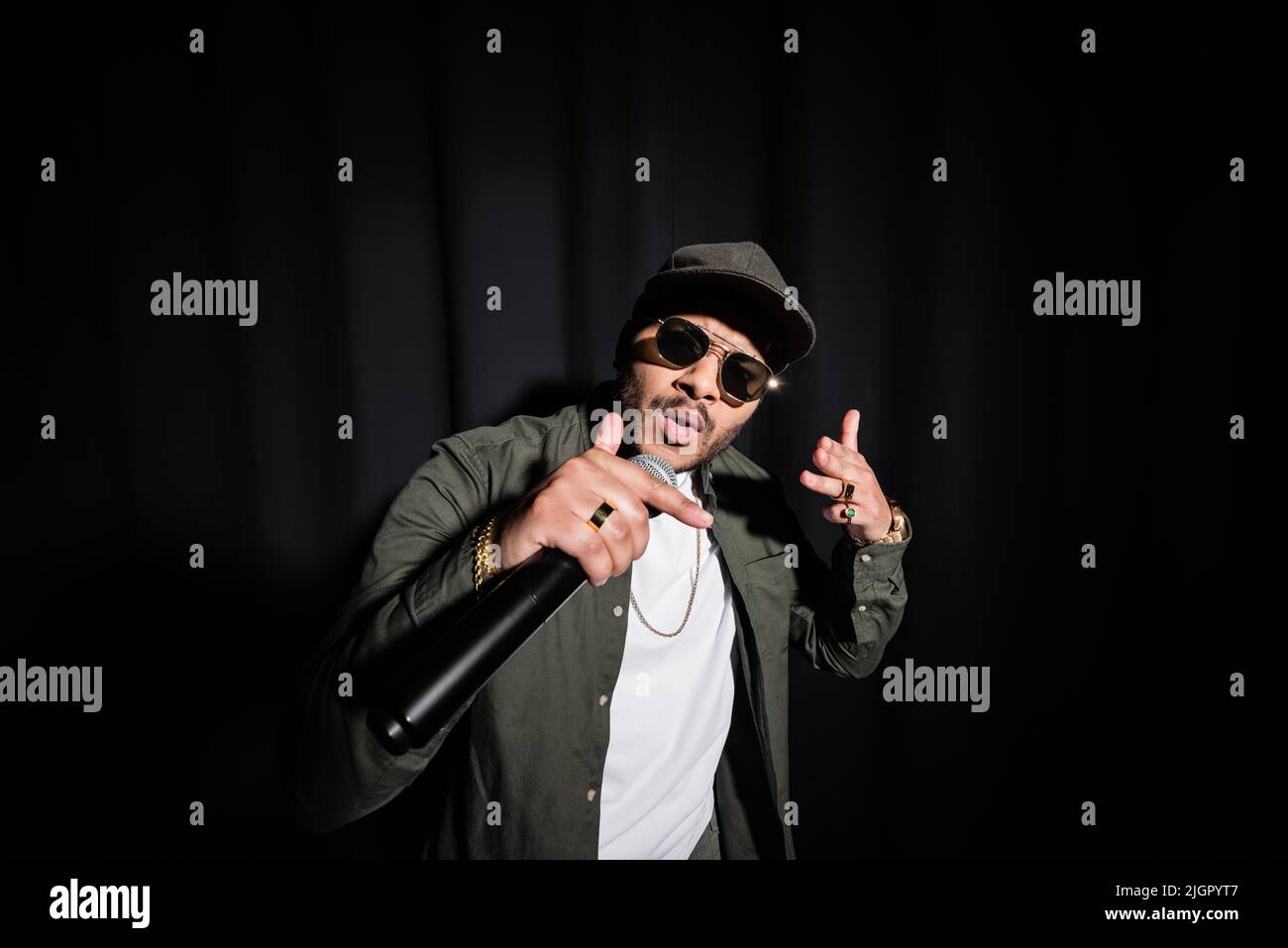 indian hip hop singer in sunglasses and cap singing in microphone on ...