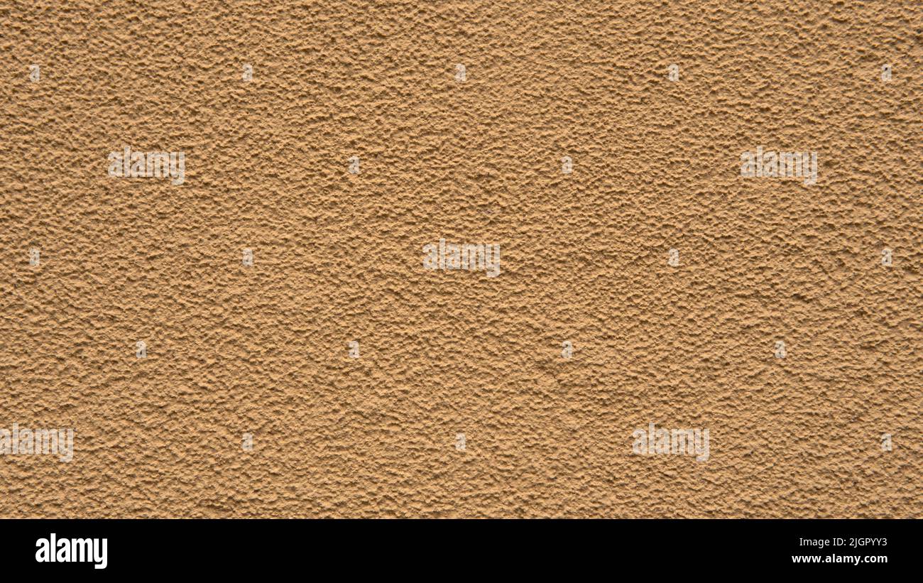 Orange creamy color and textured concrete wall of the house. Decorative ...