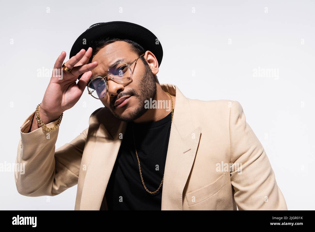 stylish indian hip hop performer in fedora hat and eyeglasses gesturing ...