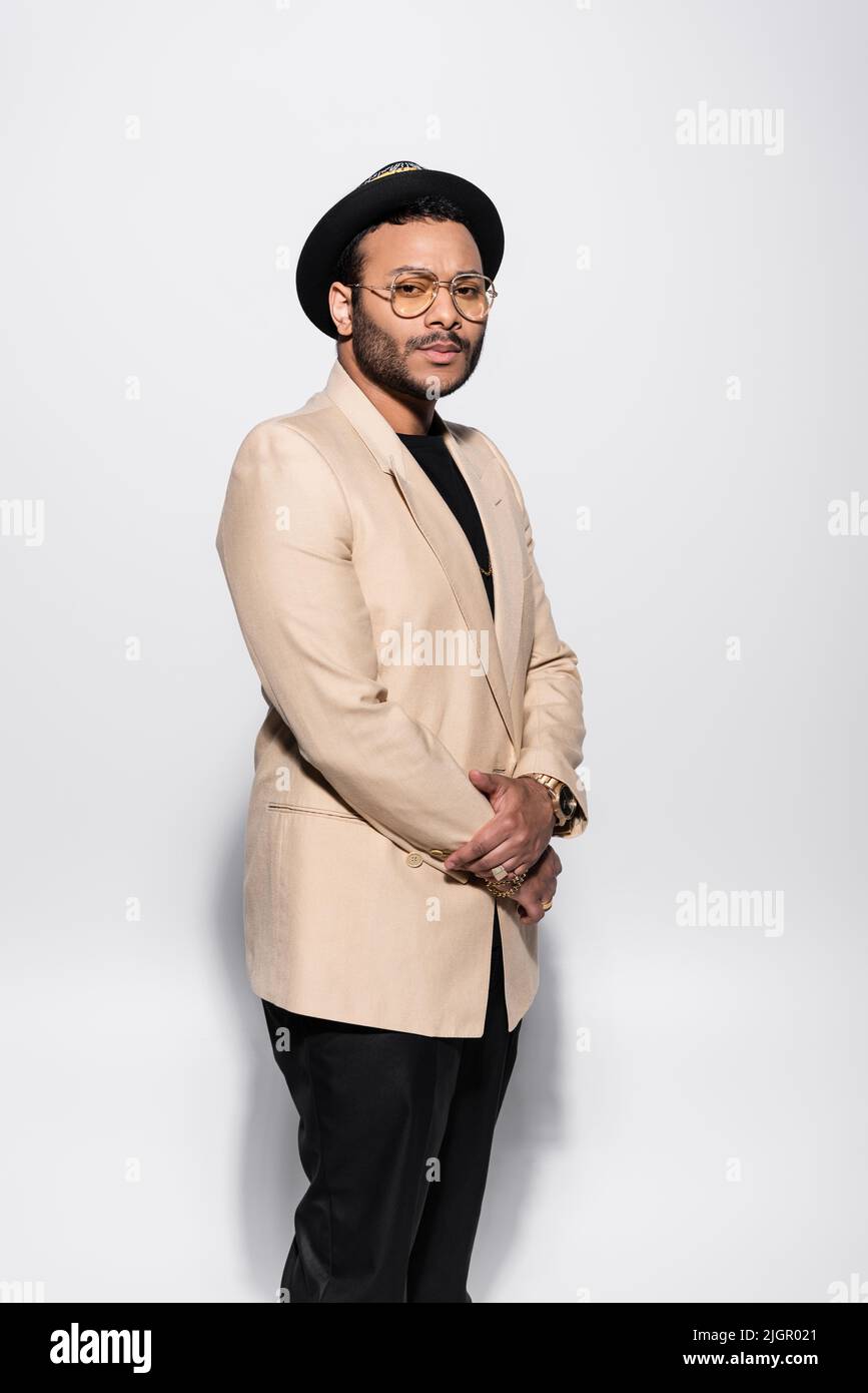 stylish indian hip hop singer in fedora hat and eyeglasses standing ...