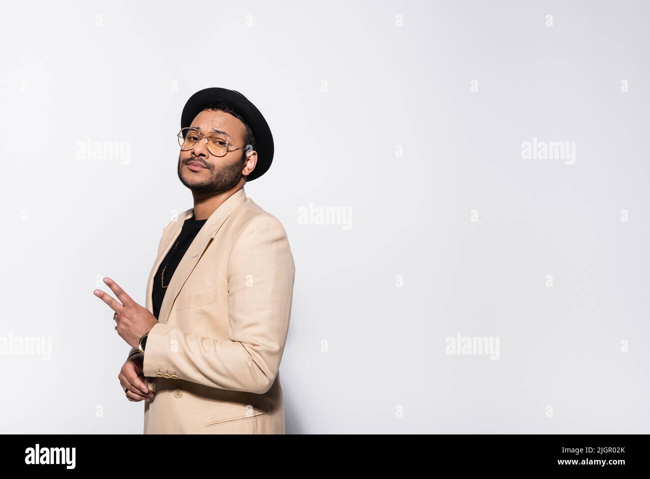 stylish indian rapper in fedora hat and eyeglasses showing peace sign ...