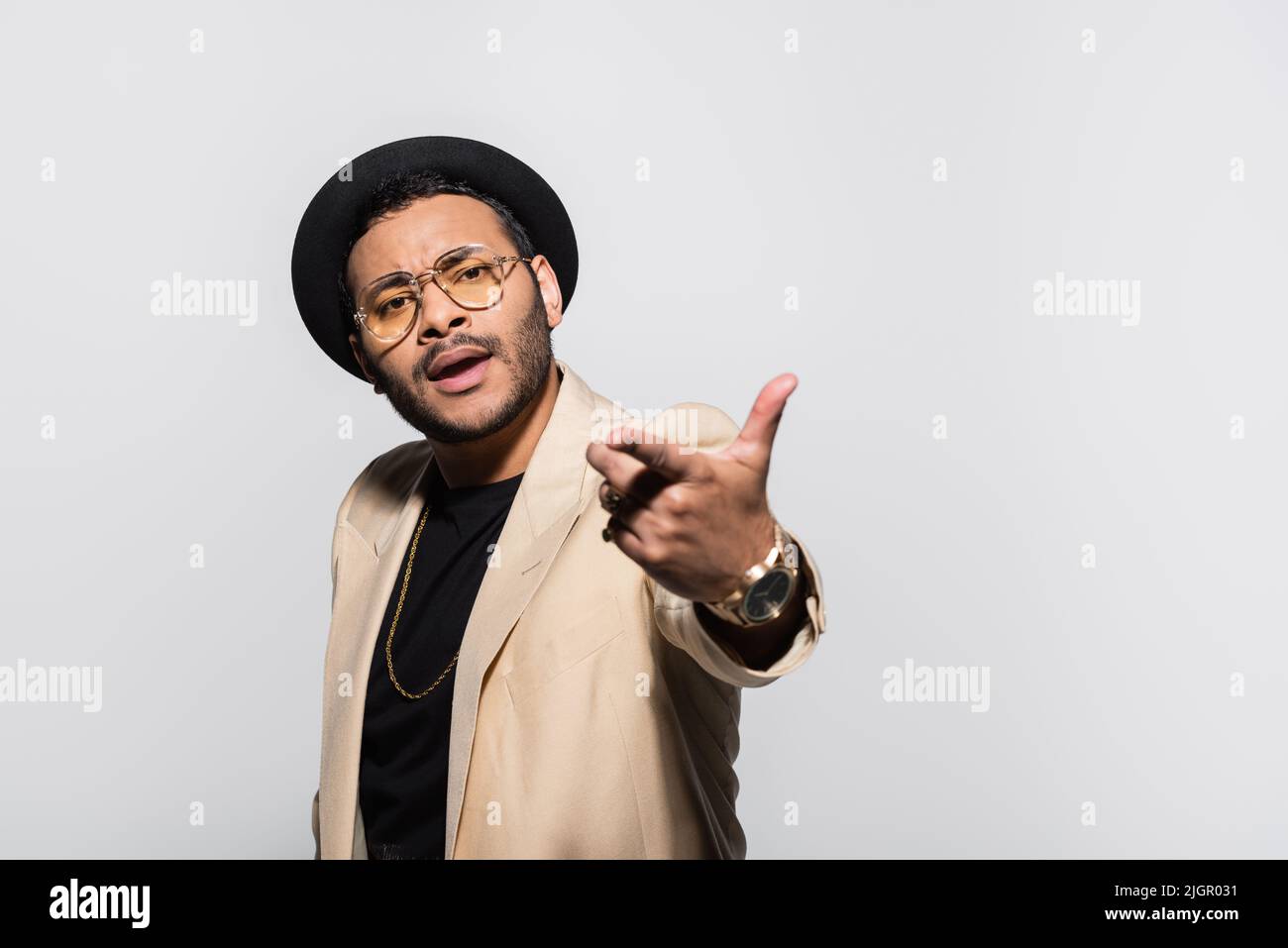 indian hip hop performer in fedora hat and eyeglasses pointing with ...