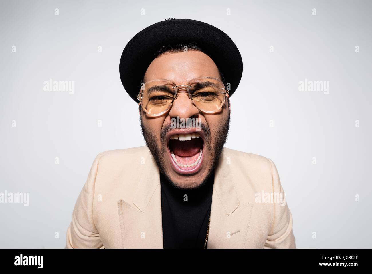 emotional indian hip hop performer in fedora hat and eyeglasses ...