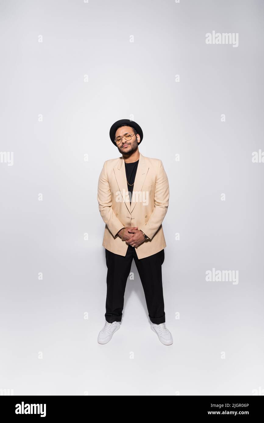 full length of stylish indian hip hop performer in fedora hat and ...