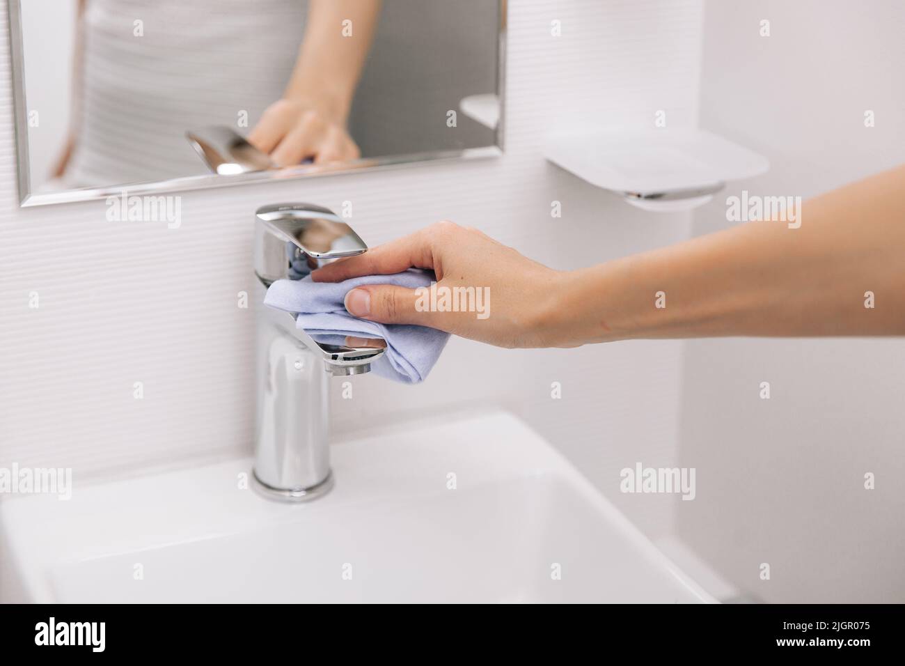 Cleaning the sink faucet with a microfiber cloth. Sanitize surfaces ...