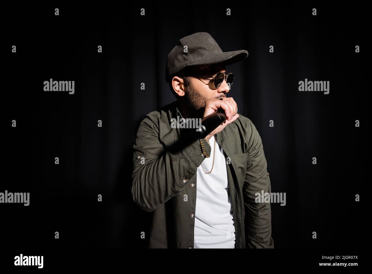 middle east hip hop singer in cap and sunglasses singing into ...