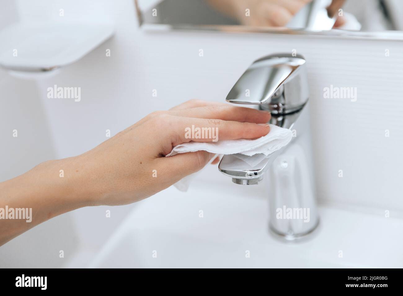Cleaning the sink faucet with a microfiber cloth. Sanitize surfaces ...