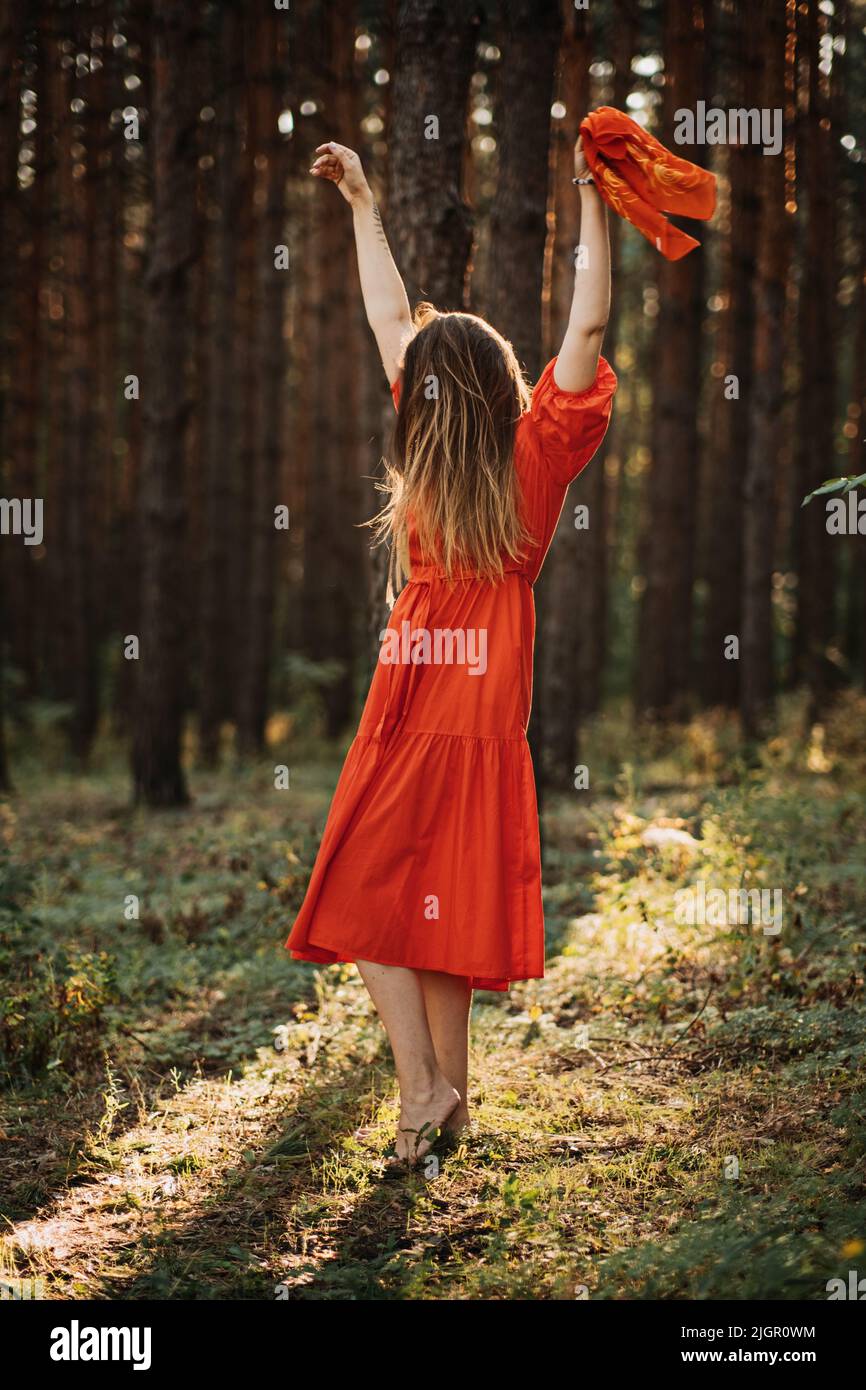 Peace of mind, breathing fresh air. Alone woman in red dress enjoys the ...