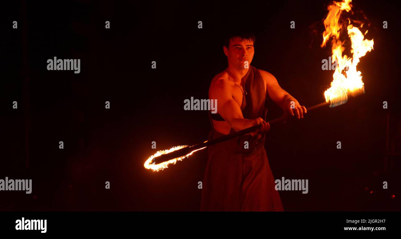Circus fire show a man stands with fire, he is half-dressed against a ...