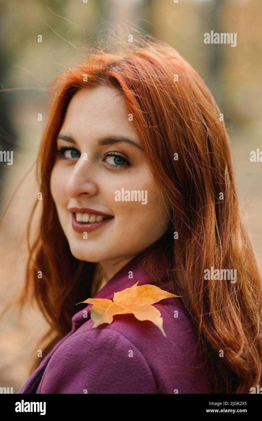 Autumn portrait of candid beautiful red-haired girl with fall leaves in ...