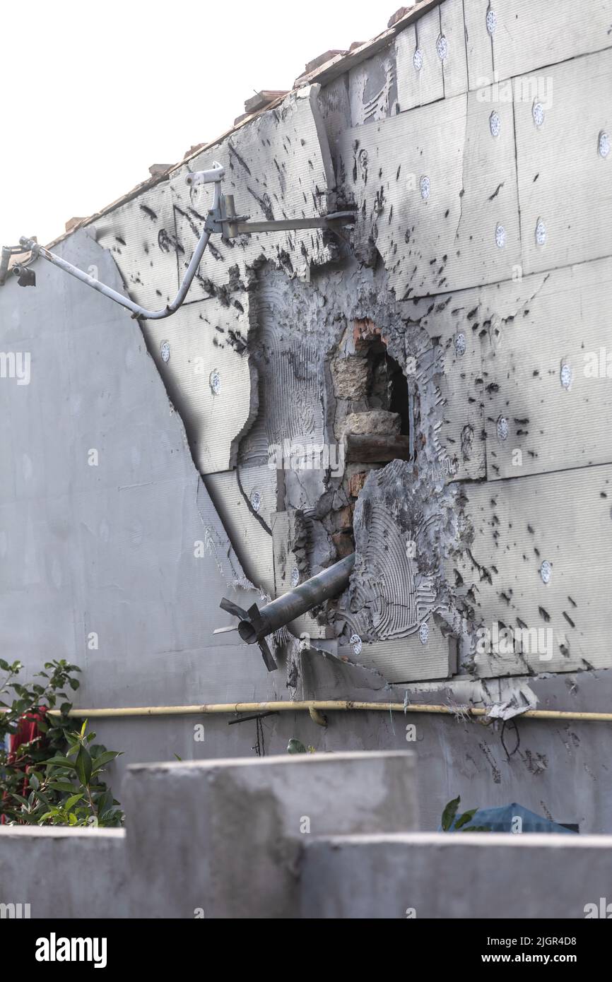 An unexploded rocket is seen in the wall of a house located in a ...