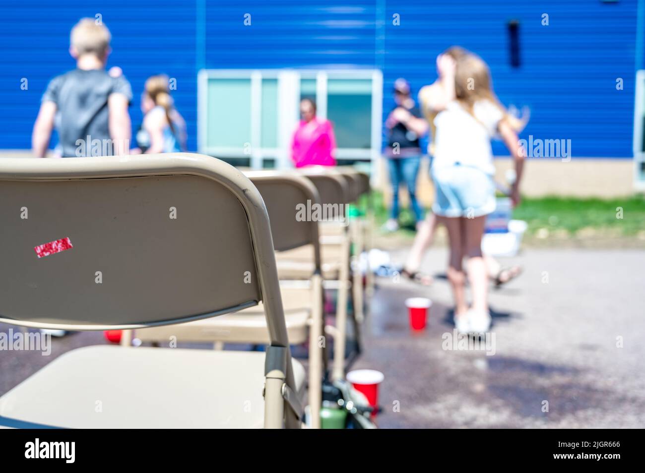 Selective focus on rows of metal folding chairs at an outdoor school ...
