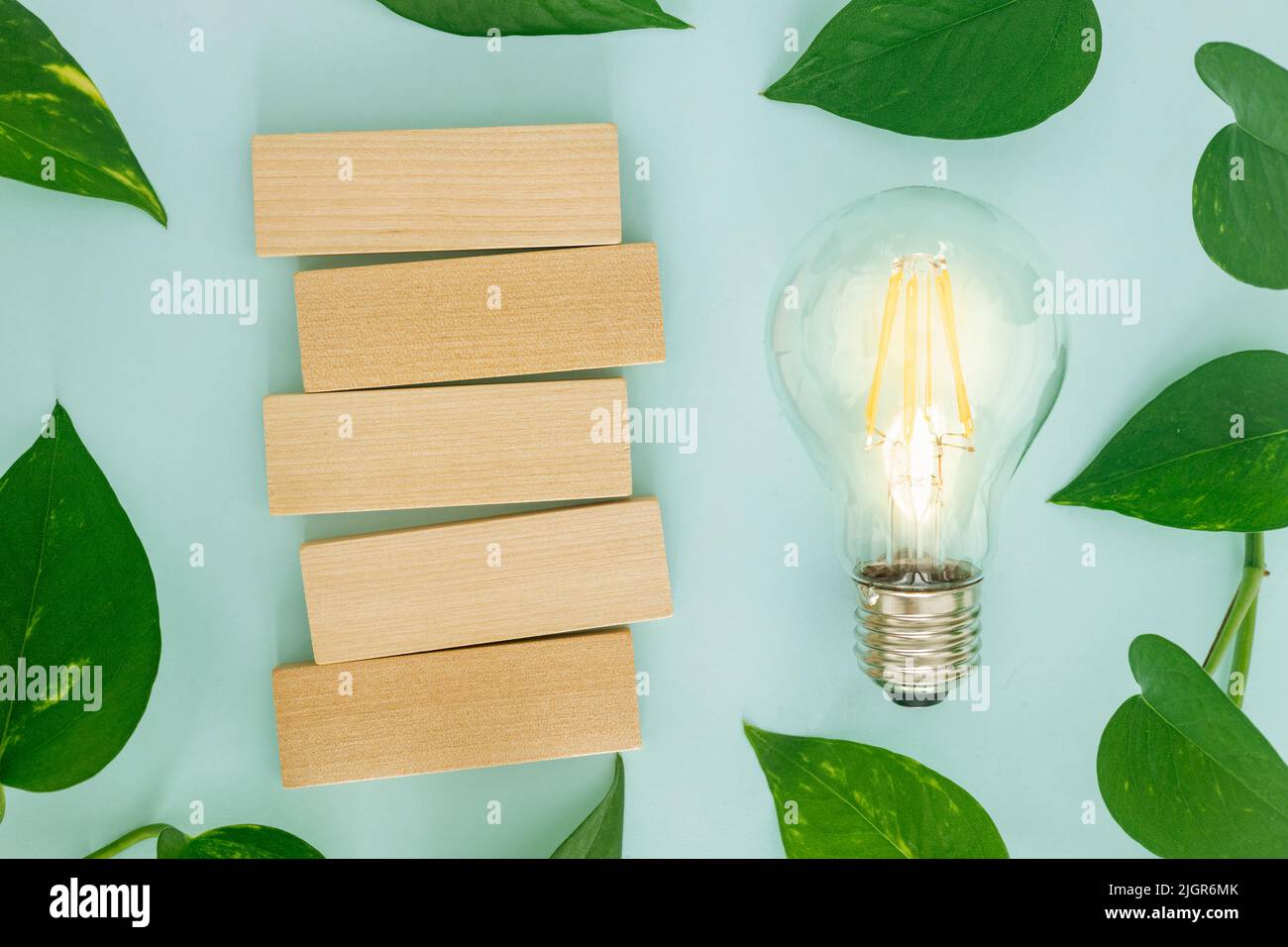 light bulb between the leaves on a light pastel background, ecological ...