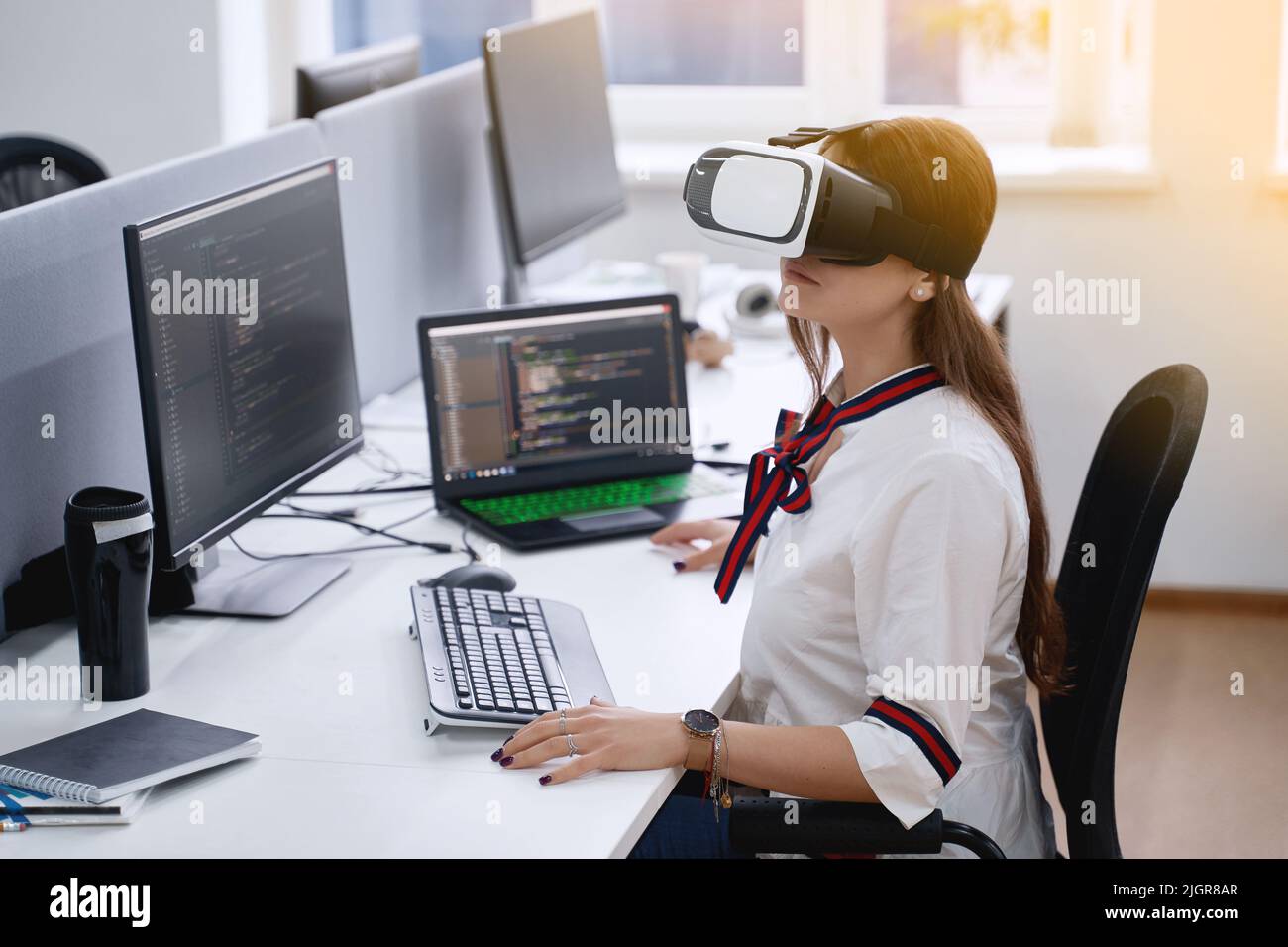 Female professional using vr virtual reality headset at desk in office ...