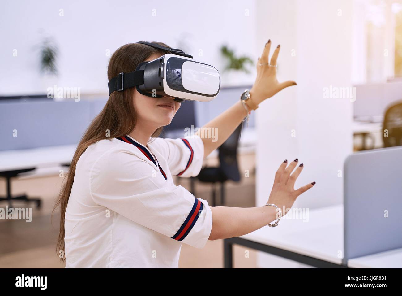 Female professional using vr virtual reality headset at desk in office ...