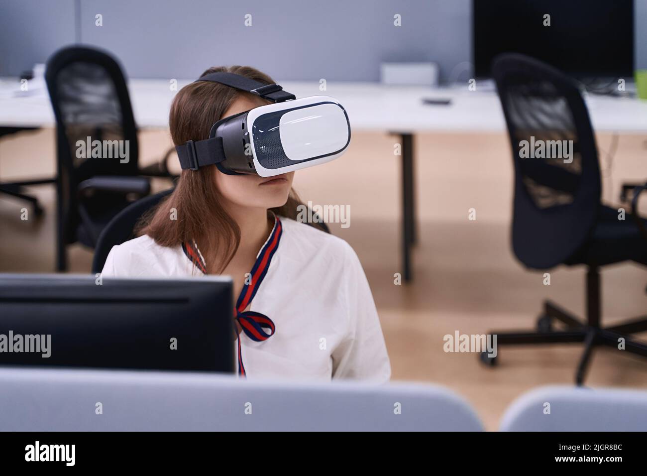 Female professional using vr virtual reality headset at desk in office ...