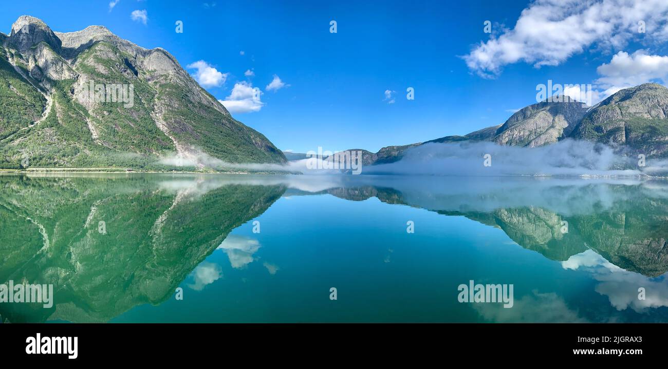 A scenic view of the reflections of Norwegian fjords in the cloudy sky ...
