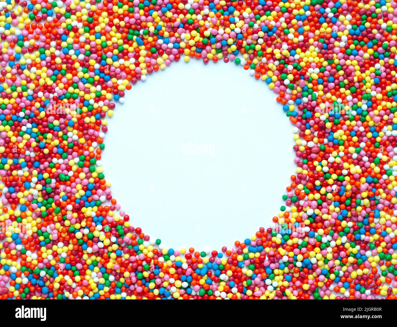 Colored sugar balls on a white background in the form of a round frame ...