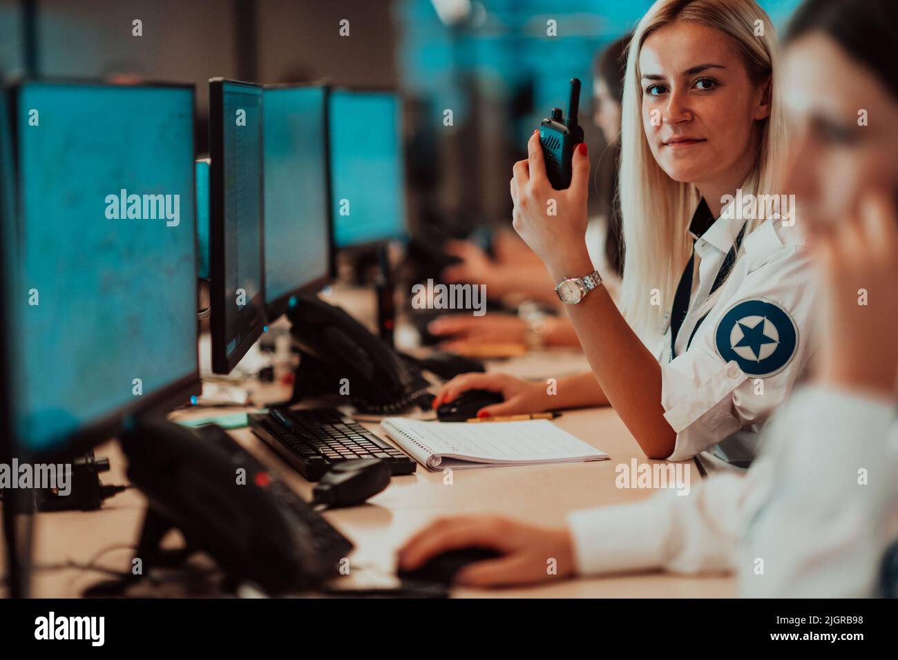 Female security operator holding portable radio in hand while working ...
