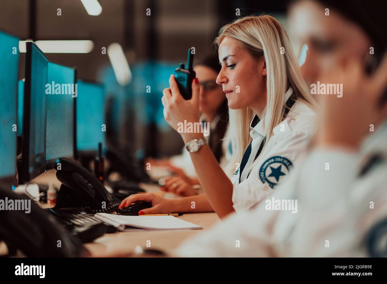 Female security operator holding portable radio in hand while working ...